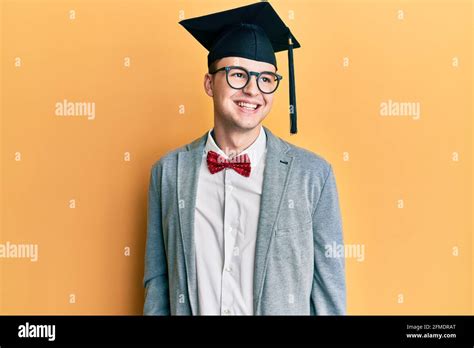 Young Caucasian Nerd Man Wearing Glasses And Graduation Cap Looking To Side Relax Profile Pose