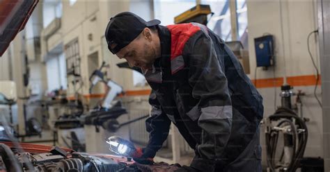작업장에서 엔진을 부수고 수리하는 동안 열린 자동차 후드 위로 구부러진 작업복의 현대 자동차 정비사 사진 Unsplash의 작업장 이미지