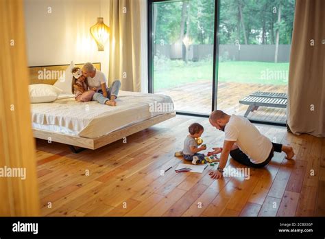 M Re Et Fille Assise Sur Le Lit Maman Embrassant L Enfant P Re Avec Son Fils Jouant Sur Le Sol