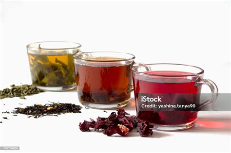 검은 색 빨간색 녹차와 세 개의 유리 컵은 흰색 배경에 마른 차 잎과 꽃이 있습니다 레드 핫 히비스커스 차 녹차 홍차 뜨거운 음료 건강한 라이프 스타일 0명에 대한 스톡