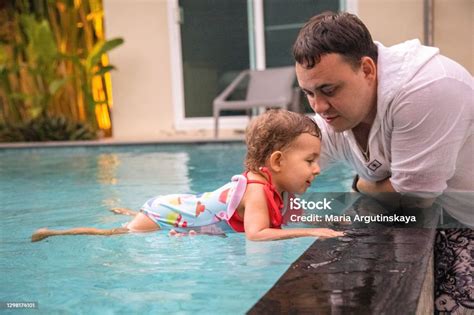 아버지는 수영복을 입은 귀여운 유아 어린 소녀를 가르치고 손을 잡고 수영장에서 수영을합니다 수영복에 대한 스톡 사진 및 기타 이미지 Istock