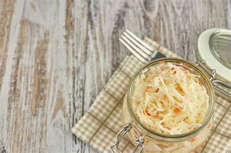 소금에 절인 양배추와 당근 빛 백색 나무 테이블 검정색 배경 항아리에 양배추의 가로 보기에 향신료와 함께 그것의 자신의 주스에의 한 항아리 전통적인 집에서 만든 0명에 대한