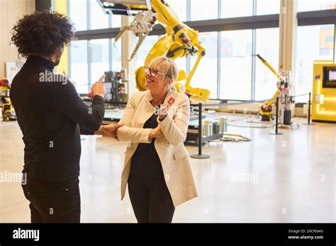 Two Engineers Engaging In Conversation About Robotics Innovations In A Modern Lab Surrounded By