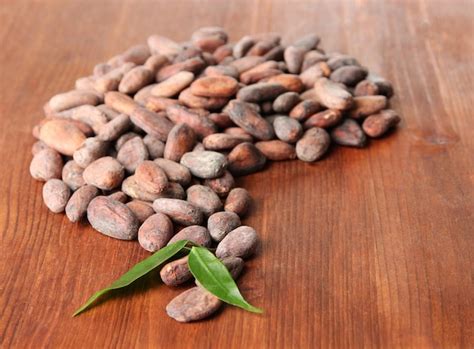 Premium Photo Cocoa Beans With Leaves On Wooden Background