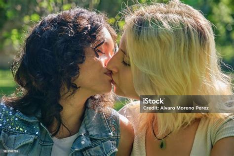 Closeup Of Young Blonde And Brunette Lesbians Kissing Illuminated By