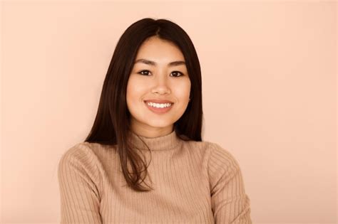 Portrait Of Cheerful Asian Girl Smiling To Camera Over Peach Background