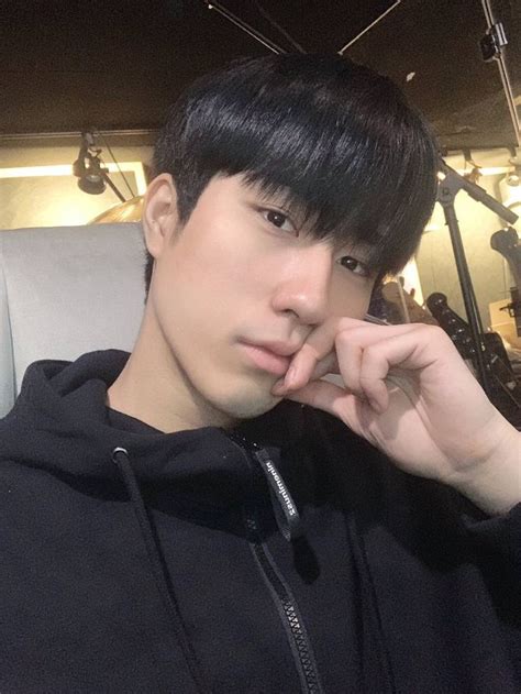 A Young Man In A Black Hoodie Is Holding His Hand Up To His Face