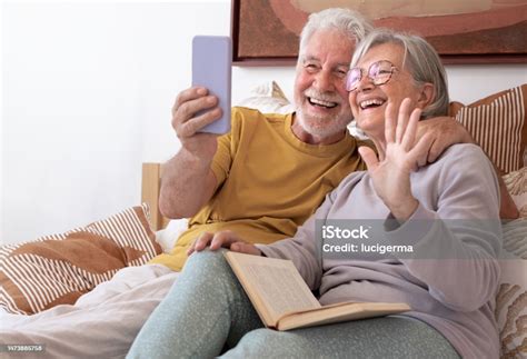 가족 및 친구들과 원격으로 의사 소통하는 노부부 침대에 앉아 스마트폰을 가진 조부모 기술 통신에 대한 개념 화상 통화에 대한 스톡 사진 및 기타 이미지 Istock