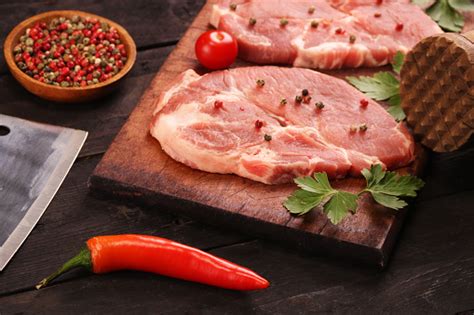 생고기 검은 배경에 야채 고추 토마토 소금과 향신료와 함께 절단 보드에 원시 돼지 스테이크 0명에 대한 스톡 사진 및 기타