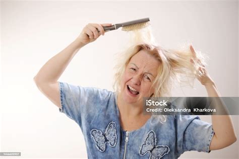 손상된 머리카락 흐트러진 빗을 가진 슬픈 성인 여성은 솔질되지 않은 마른 머리카락을 손에 들고 있는 여성 모델의 초상화를 근접 촬영합니다 모발 손상 건강 및 미용 개념