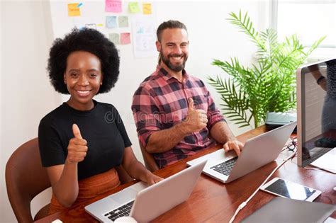 Two Developers Sitting At Shared Desk Give Thumbs Up Coding In Office
