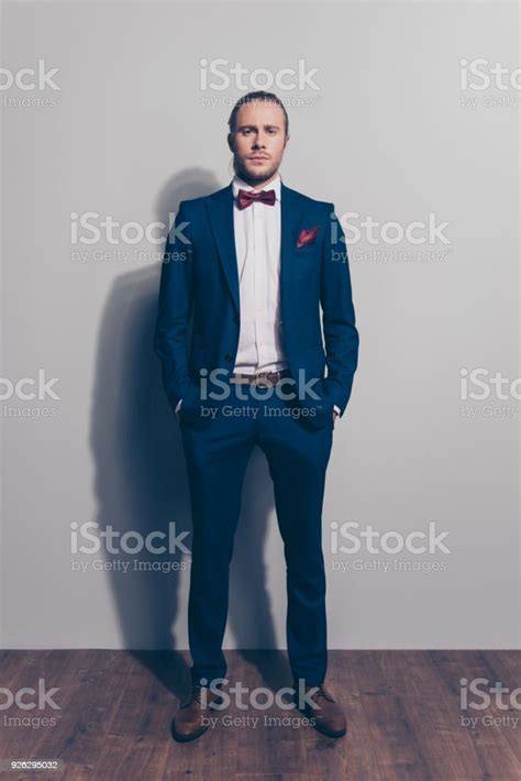 전체 길이 Bowtie와 손수건 파란 양복에 회색 배경 위에 카메라를 보고 심각한 표정으로 주머니에 그의 손을 잡고 우아한 남자의 초상화 개성 개념에 대한 스톡 사진 및