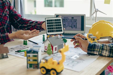 기술자와 엔지니어가 만나 주거용 프로젝트에 태양 전지와 풍력 터빈을 설치하는 것에 대해 논의합니다 태양 에너지는 미래에 중요한 에너지원이 될 것입니다 클로즈업 사진 전기공에