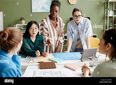 Group Of Female Architects Working Over New Construction Project At Table With Blueprint And