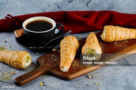 냅킨에 분리된 블랙 커피 한 잔과 함께 나무 판에 제공되는 크림 롤 또는 크림 빵은 프렌치 브렉퍼스트 구운 음식의 측면 모습입니다 0명에 대한 스톡 사진 및 기타 이미지