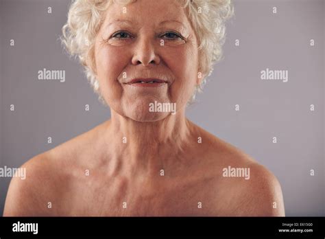 Portrait Of Naked Old Woman Against Grey Background Head And Shoulders Of Senior Female With