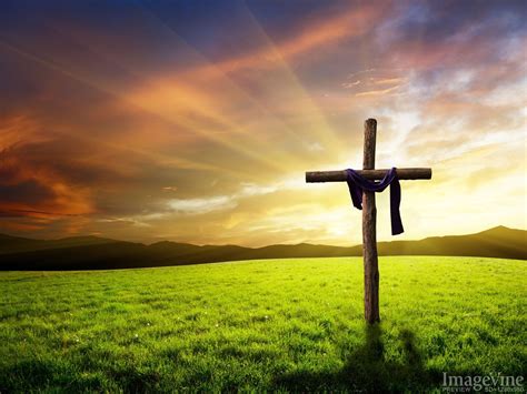 A Cross In The Middle Of A Grassy Field With Sun Shining Through Clouds