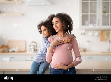 Black girl hugging her pregnant mom from the back Stock Photo - Alamy