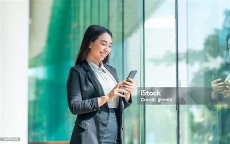 따뜻한 일출 빛과 함께 현대적인 사무실 건물에서 스마트 폰을 사용하는 아시아 사업가 25 29세에 대한 스톡 사진 및 기타 이미지 25 29세 Brand Name