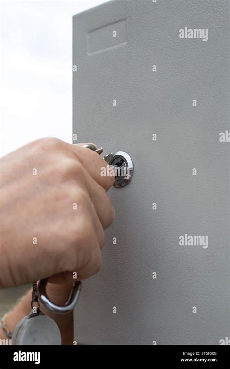 A Man Closes The Lock On The Electrical Panel Cover Security Of Power