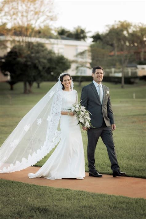 감정 걷고 있는 격식있는 옷차림 결혼 사진 결혼 한 커플 경치 관계 꽃꽂이 끈 나무 낭만적인 낮 녹지 단란함 로맨스 미소 짓는 베일 부케