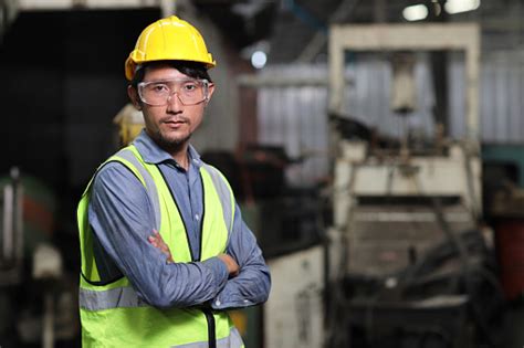 자신감 있는 아시아 기술자 엔지니어와 보호복을 입은 노동자가 서서 시선을 돌리며 산업 제조에서 산업 기계 공정을 점검하는 작업을 제어하고 있다 25 29세에 대한 스톡 사진