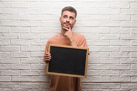 질문 매우 혼란 스 러 워 아이디어에 대해 칠판 심각한 얼굴 생각 들고 벽돌 벽을 통해 젊은 성인 남자 개념에 대한 스톡 사진