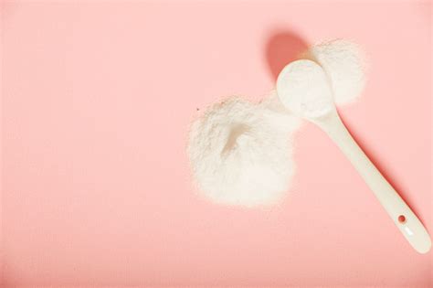 분홍색 배경에 콜라겐 파우더 추가 단백질 섭취 피부 뼈 관절 및 장건강을 위한 천연 미용 및 건강 보조 식품 식물 또는 생선 기반 플랫레이 상단 보기 텍스트의 공간을