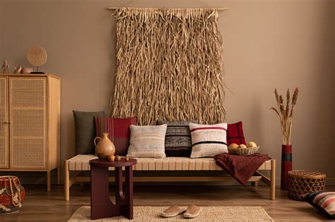 화려한 베개 등나무 찬장 부르군트 커피 테이블 말린 꽃병 슬리퍼 및 개인 액세서리가있는 Ethno 거실 인테리어의 인테리어 디자인 가정 장식 템플렛 실내 장식에 대한 스톡