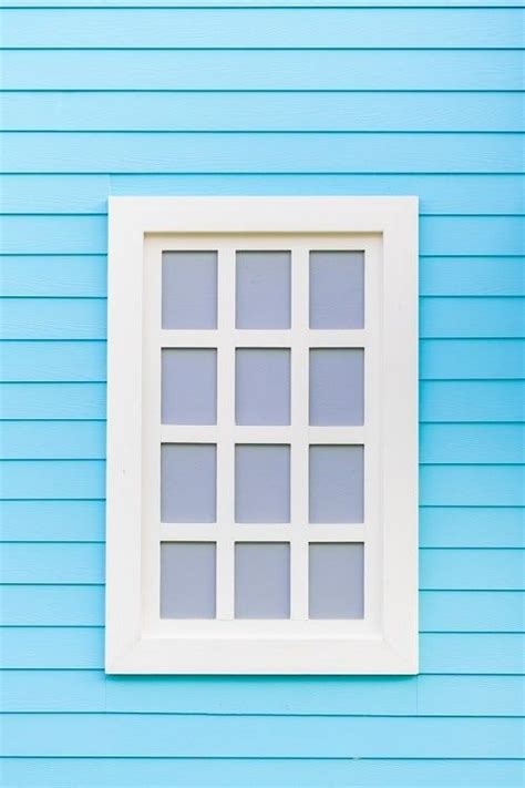 A Window On The Side Of A Blue Building With White Trim And Squares In It