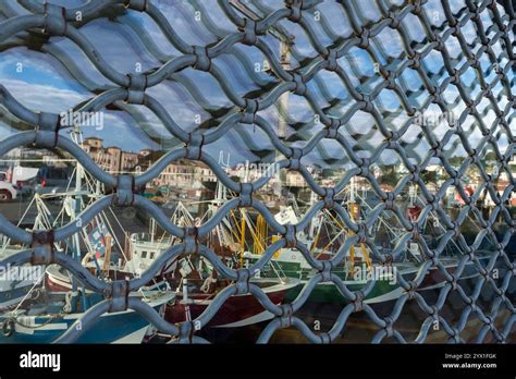 A Shuttered Storefront Window Display With Fishing Boat Models Reflects The Village Waterfront