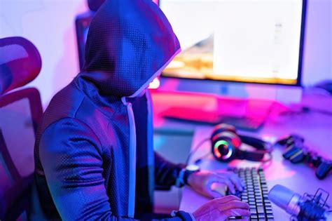 premium photo hacker wearing hood jacket typing computer keyboard to