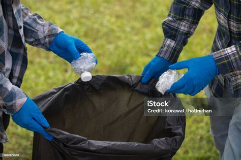 두 명의 직원이 검은색 쓰레기 봉투를 사용하여 잔디밭과 보도에서 플라스틱 병과 재활용 가능한 폐기물을 수거하여 재활용합니다 재활용을 위한 플라스틱 폐기물 분류의 개념 2명에