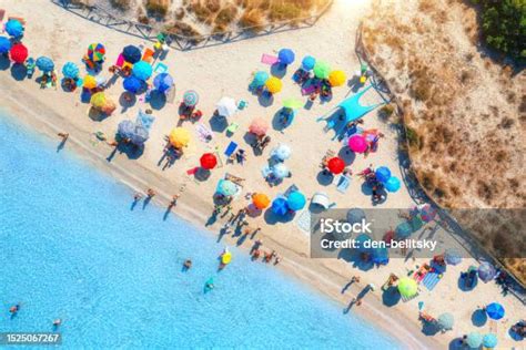 모래 해변에 화려한 우산의 공중 전망 여름에 일출에 푸른 바다에서 수영하는 사람들 사르데냐 이탈리아 맑은 푸른 물이 있는 열대 풍경 여행과 휴가 상단 드론 보기 공중 뷰에
