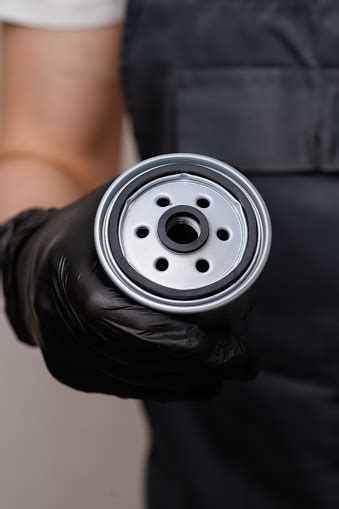장갑을 낀 자동차 정비사가 디젤 자동차의 연료 필터를 손에 들고 클로즈업하여 돌립니다 자동차 유지 보수 및 수리 연료 필터 교체 자동차 부품의 전문 교체 세로 건강 진단에