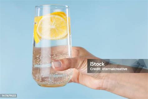 여자 손은 파란색 배경에 단단한 셀처 앞면의 수제 칵테일 한 잔을 들고 있습니다 탄산수에 대한 스톡 사진 및 기타 이미지