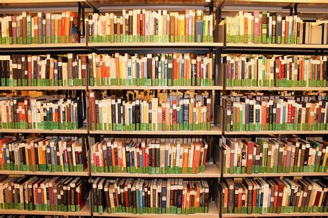 На книжной полке стоят книжные тома в беспорядке - фото