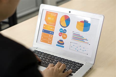 정장을 입은 사업가의 뒷모습은 사무실의 책상에 앉아 노트북 컴퓨터 키보드로 타이핑하고 그래프와 여러 가지 색상의 차트로 프리젠