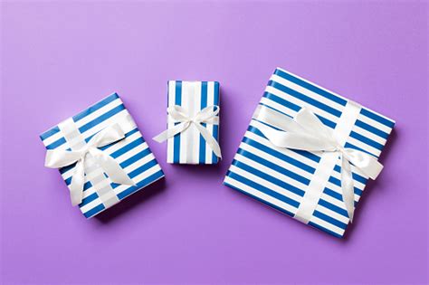 ห่อคริสต์มาสหรือวันหยุดอื่นๆที่ทําด้วยมือในปัจจุบันในกระดาษที่มีริบบิ้นสีขาวบนพื้นหลั ภาพสต็อก