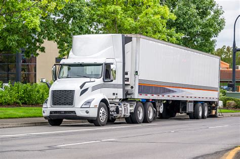 현지 배송 데이 캡 지붕 스포일러가 있는 대형 장비 세미 트럭 냉장고 세미 트레일러 도시 거리에 서 있는 낮은 리프팅 플랫폼이 있는 세미 트레일러 차에 대한 스톡 사진 및