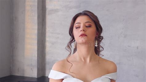 A Pretty Girl In A White Dress Poses For A Photographer Turning Her