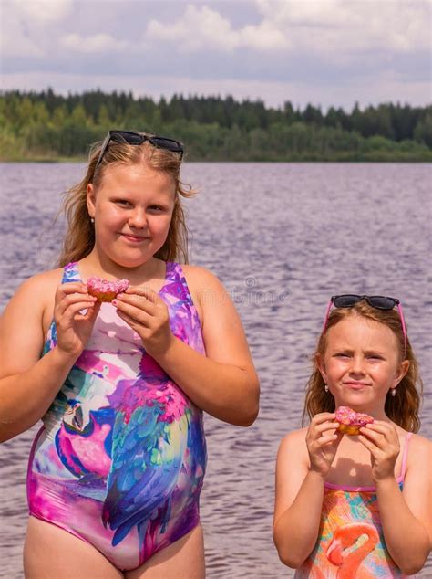 On A Hot Summer Day On The Beach The Girls Are Holding Pink Donuts In