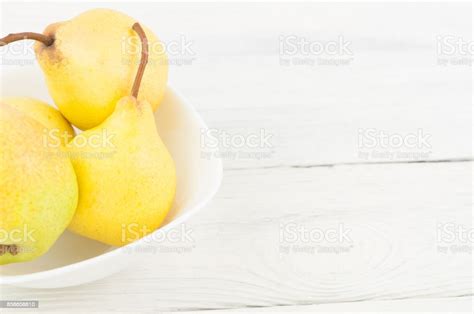 오래 된 소박한 흰색 나무 테이블에 흰색 세라믹 그릇에 신선한 익은 노란색 전체 배나무의 힙 건강한 식생활에 대한 스톡 사진 및
