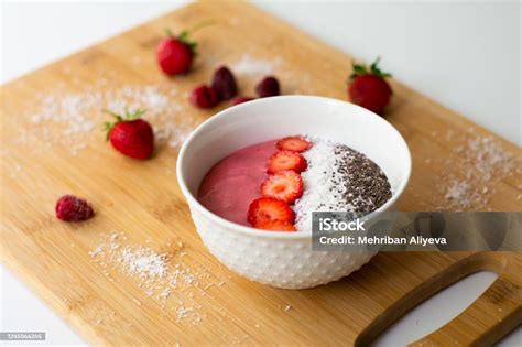 건강한 비건 트렌디한 아침 식사 냉동 바나나 라즈베리 딸기 코코넛 밀크로 만든 마젠타 핑크 베리 스무디 보울 코코넛 플레이크 치아 씨앗과 슬라이스 딸기를 얹습니다 0명에