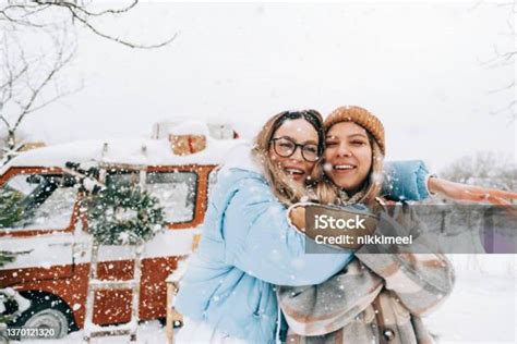 겨울 캠프에서 눈이 내리는 동안 밴 근처에서 야외에 서있는 두 명의 쾌활한 여성 친구의 초상화 겨울에 대한 스톡 사진 및 기타 이미지 Istock