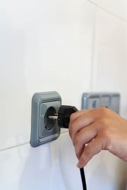 Premium Photo Woman Inserting The Plug In The Kitchen Socket