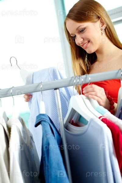 Фотография на тему Девушка выбирает одежду в магазине Pressfoto