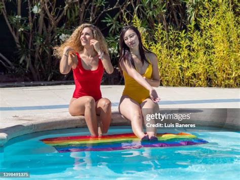 Cheerful Young Diverse Lesbians In Swimsuits Sitting At Poolside High