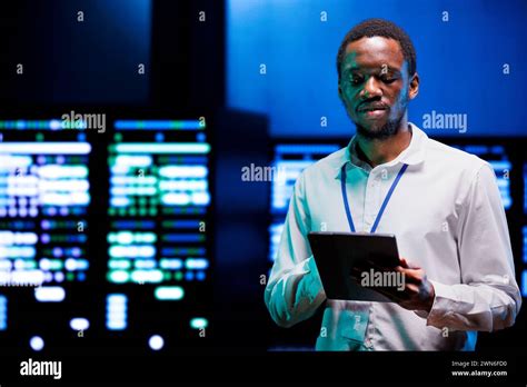Focused Admin Using Tablet To Assess Energy Consumption Across Server Rackmounts Components