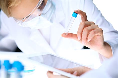 과학 연구 팀의 실험실에서 솔루션 선택을 취소 합니다 금발 여성 화학자 그녀의 동료 결과 태블릿 Pc 검사 하는 동안 유리의 테스트 튜브를 보유 하고있다 혈액 검사 약 또는